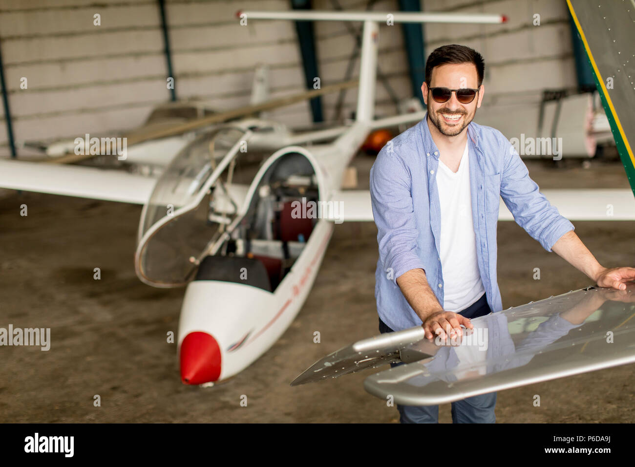 Handsome young pilot checking airplane in the hangar Stock Photo - Alamy