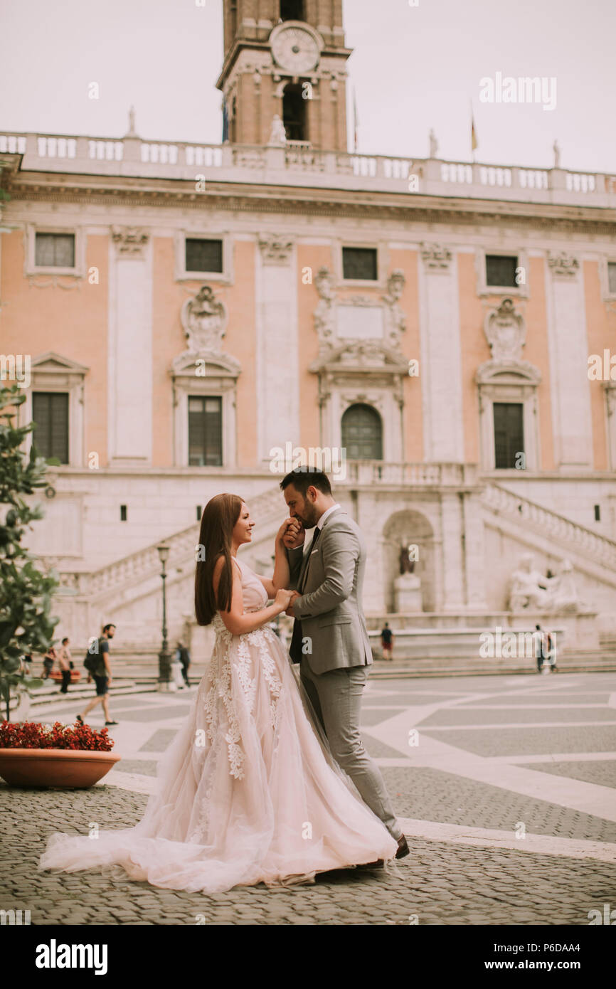 Young attractive newly married couple walking and posing in Rome with ...