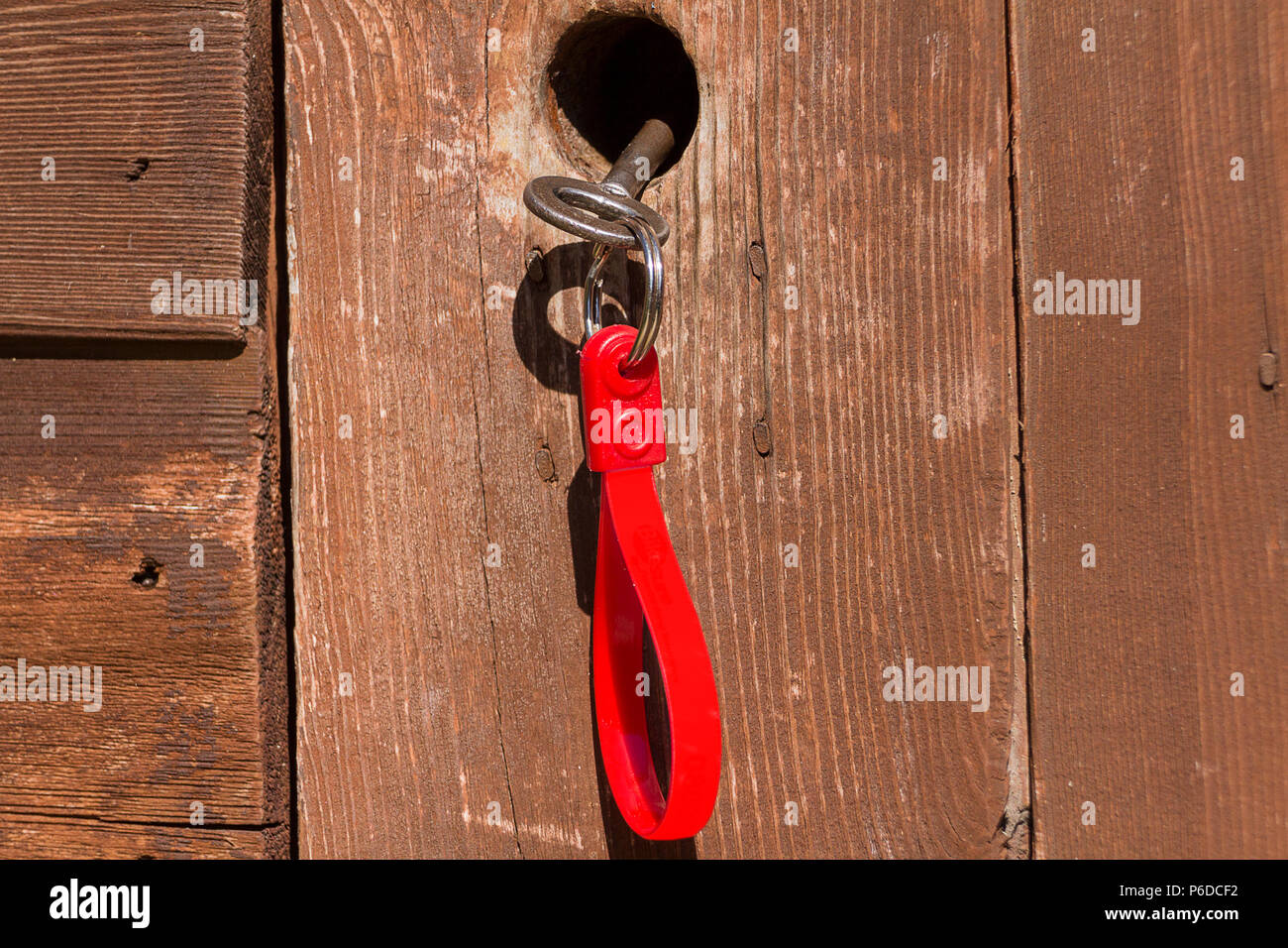 Shed lock and key with bright red tag against weathered and worn timber ...