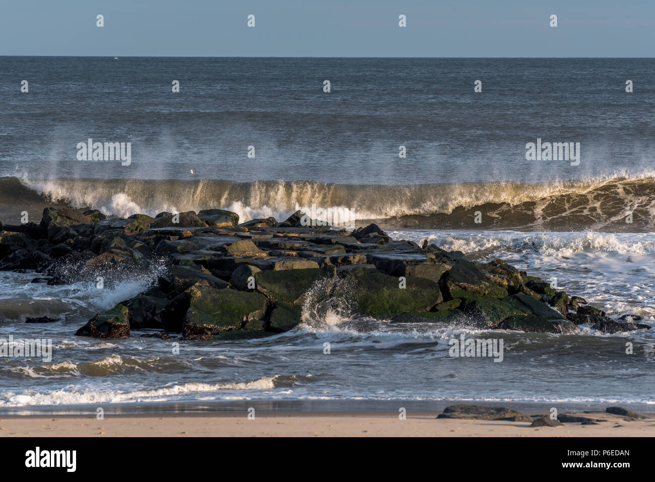 Waves crash against a jetty on the Spring Lake Beach in winter Stock ...