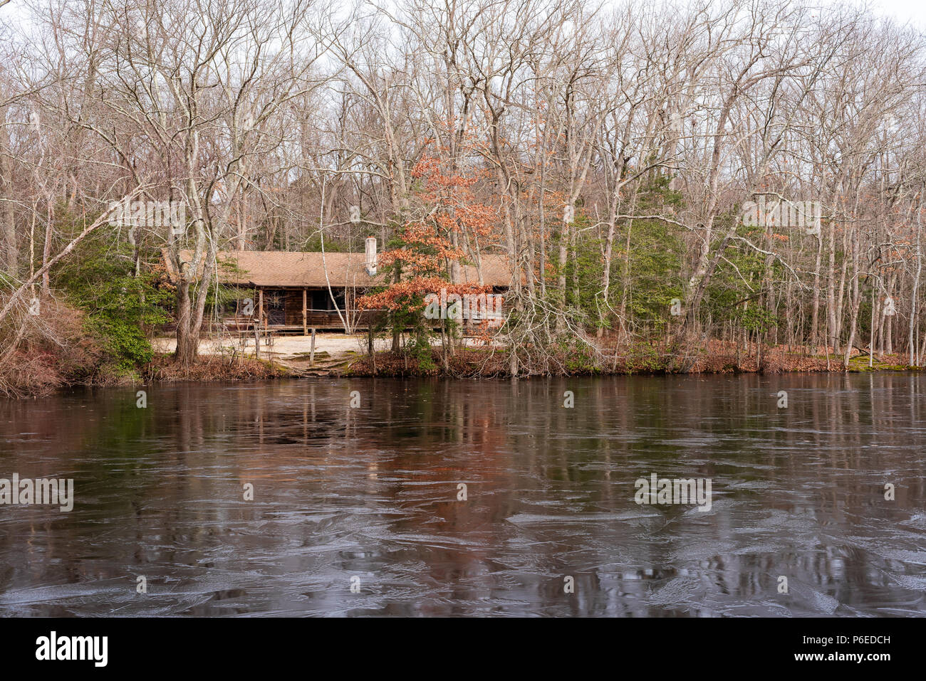 A lake is freezing over in front of a cabin in the woods Stock Photo ...