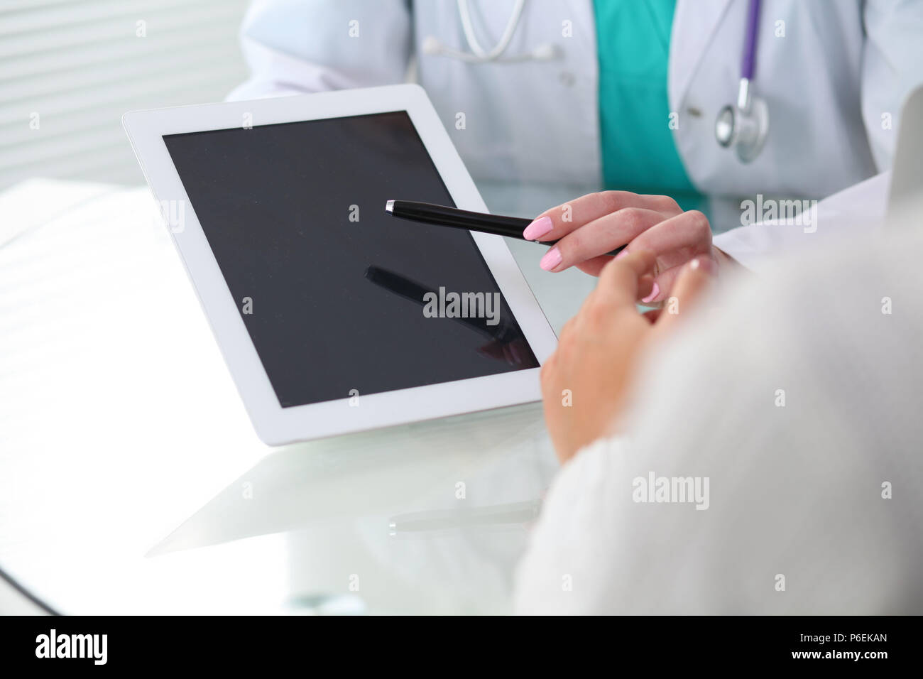 Doctor and patient, close-up. Physician pointing into laptop computer ...