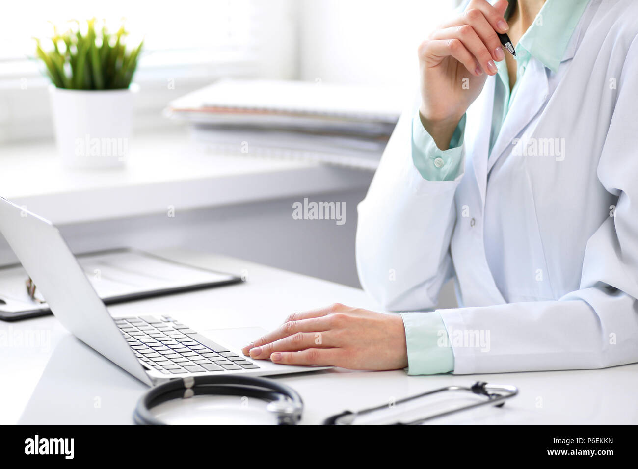 Close up of unknown female doctor sitting at the table near the window ...