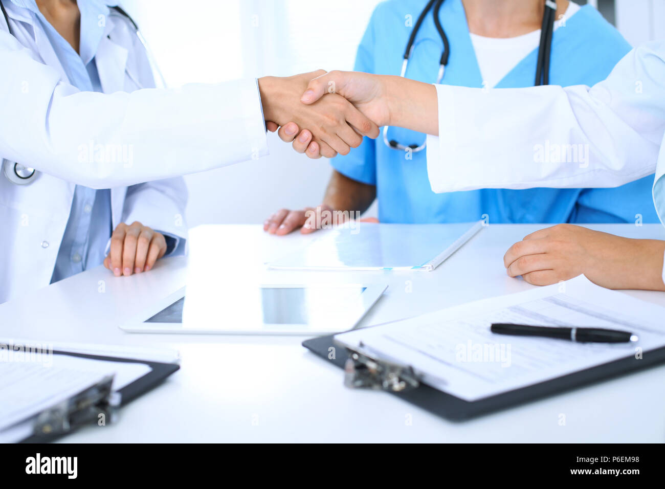 Two doctors shaking hands to each other at meeting. Teamwork and ...