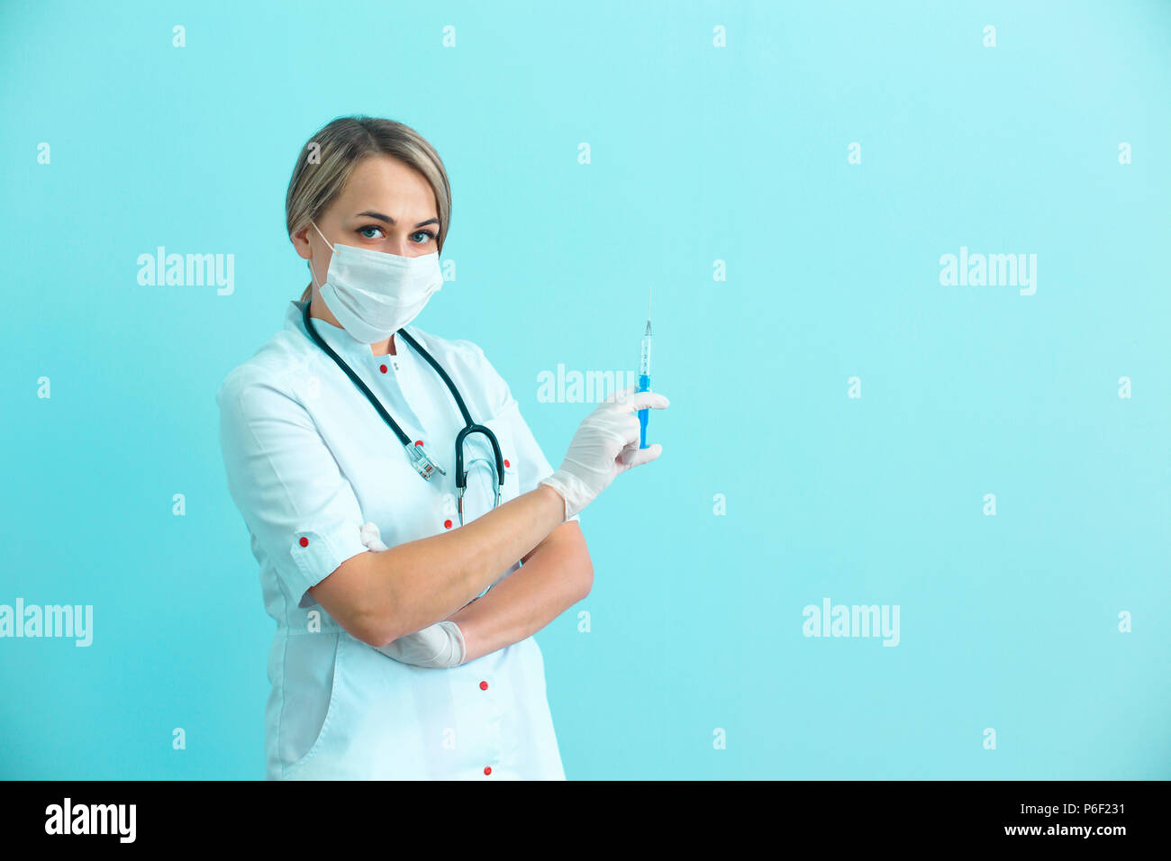 Female doctor with protective mask is holding injection on blue ...
