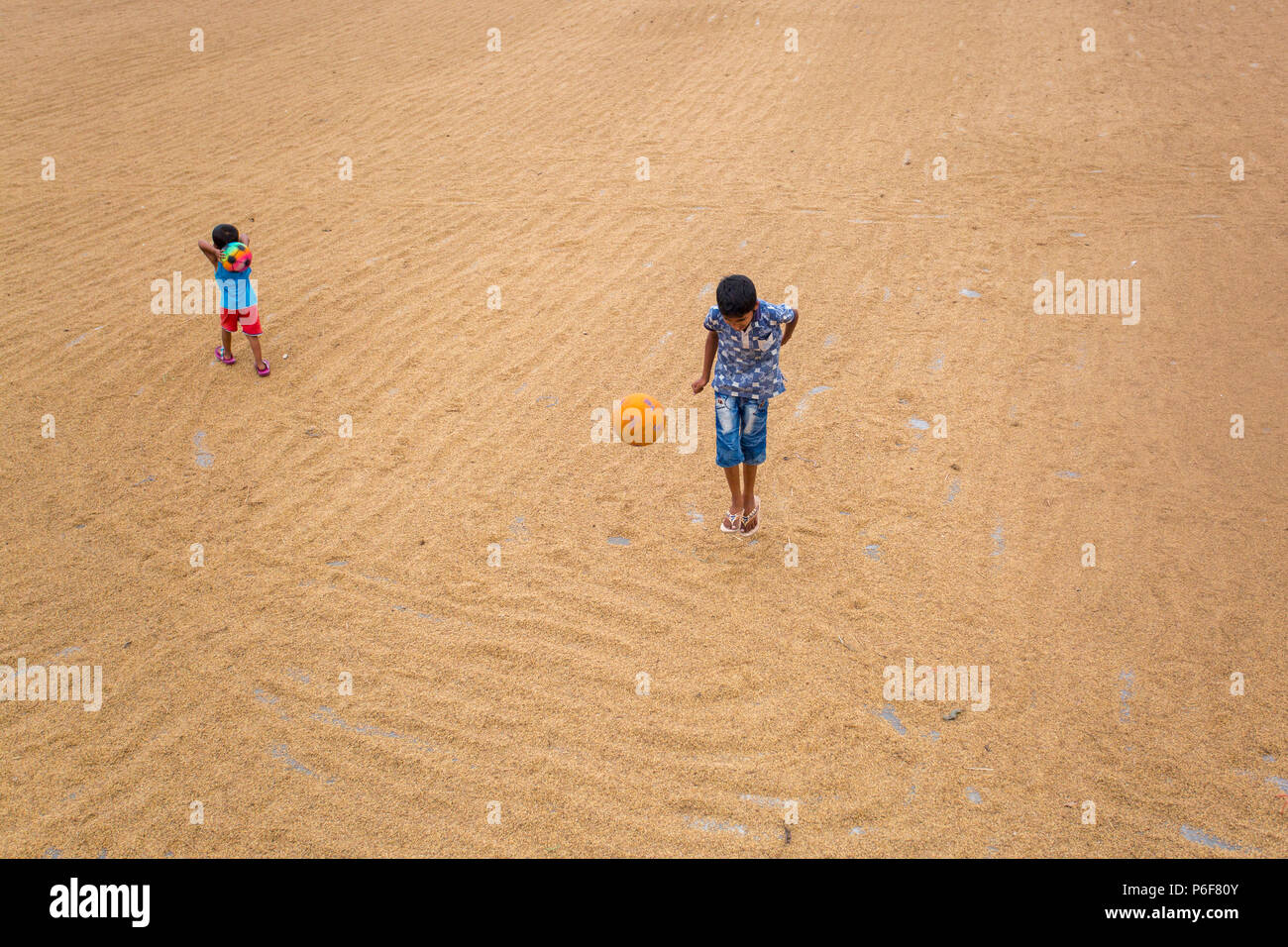 Some of the children are playing football on dry paddy in the sun at ...