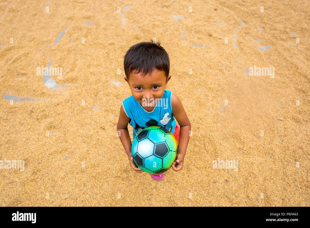 Some of the children are playing football on dry paddy in the sun at ...