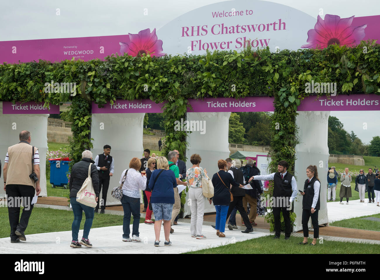 People arriving & walking to entrance gate, event staff working ...