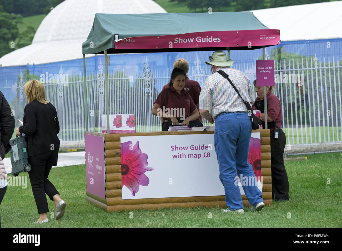 Rear view of man, buying show guide from woman working on stall by ...