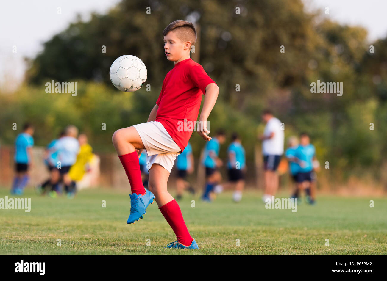 Boy kicking football on the sports field during soccer match Stock ...