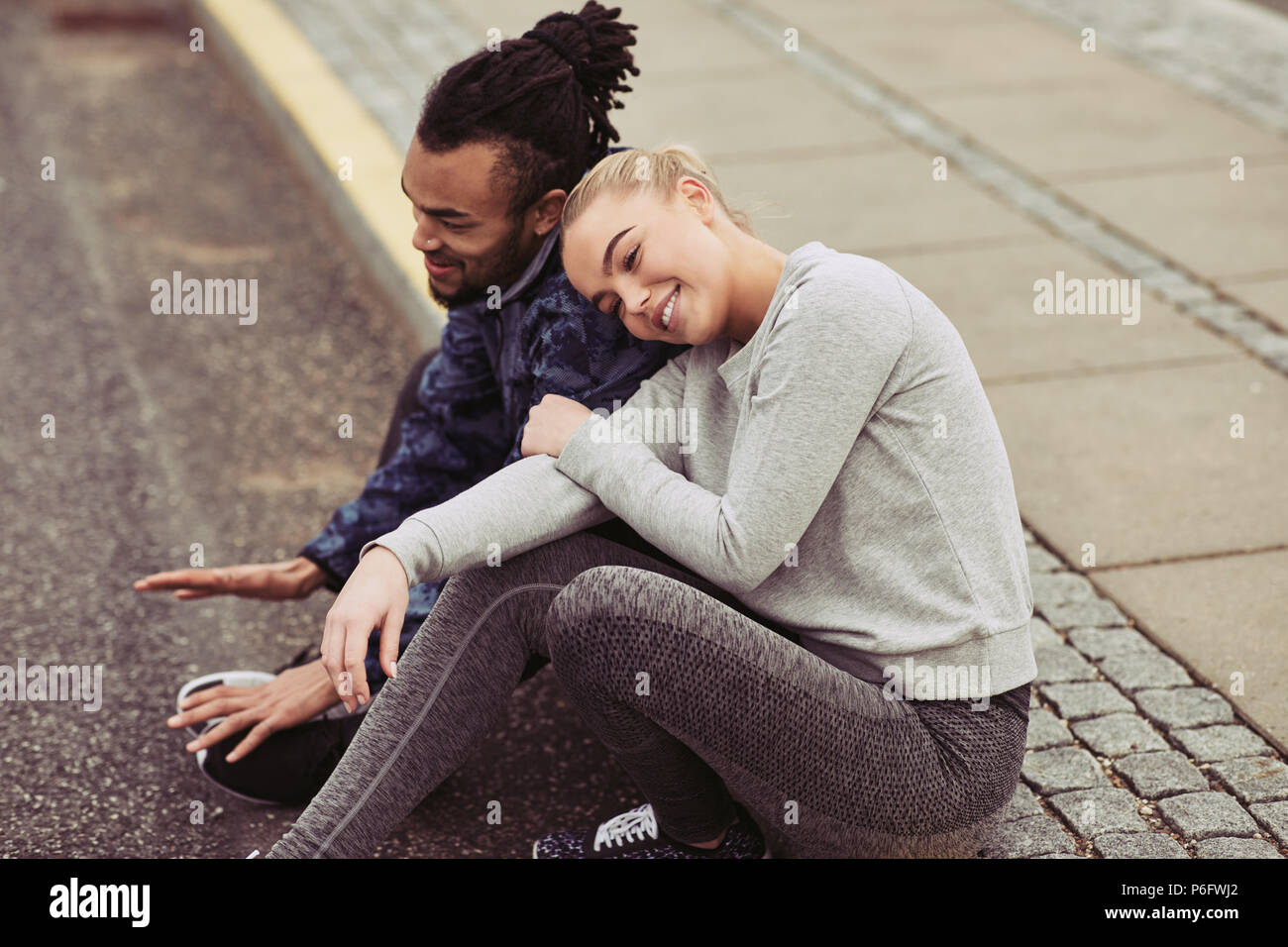 Smiling young woman resting her head on her boyfriend's shoulder while ...