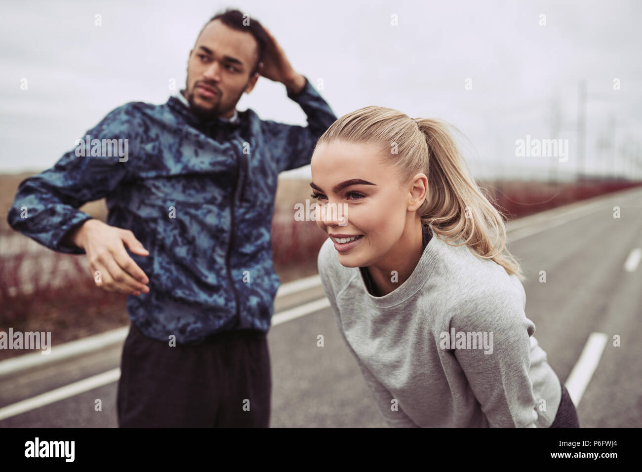 Smiling young woman in sportswear preparing for a run with her ...
