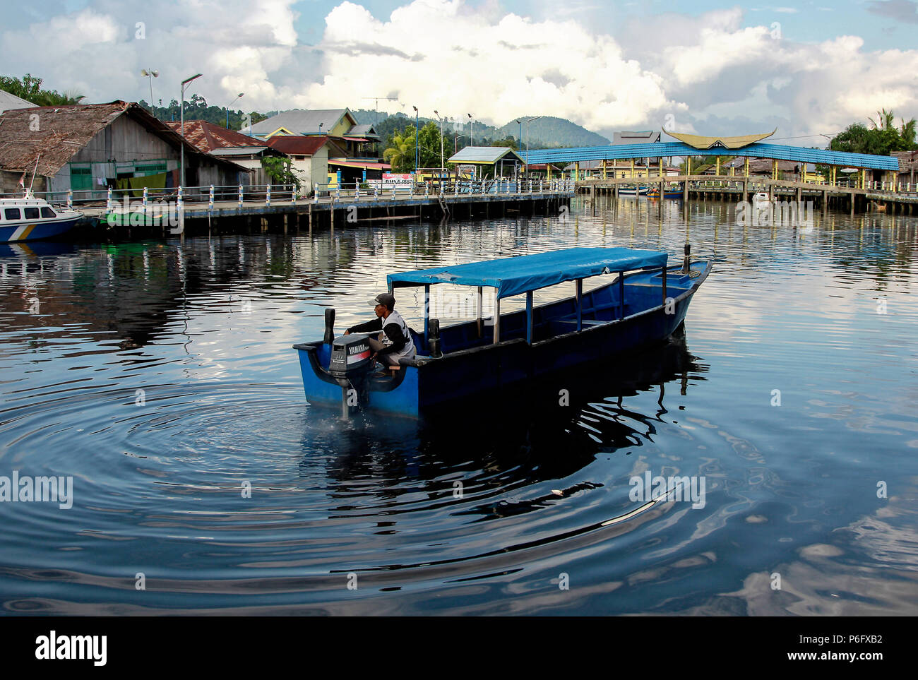 A fisherman prepares his boat in a flowing canal on Bacan Island, North ...