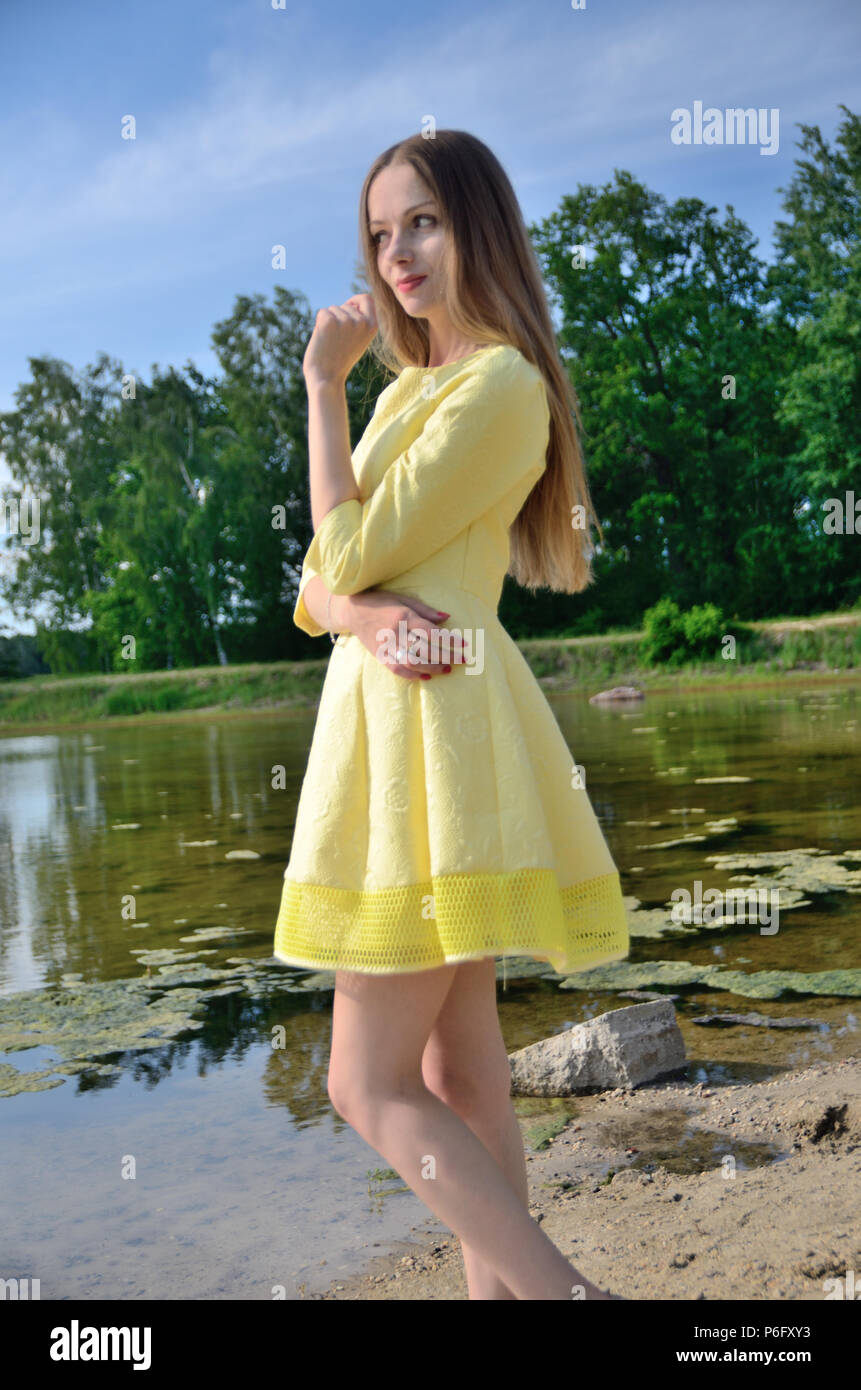 Petite woman at lake. Female model with yellow dress standing near ...