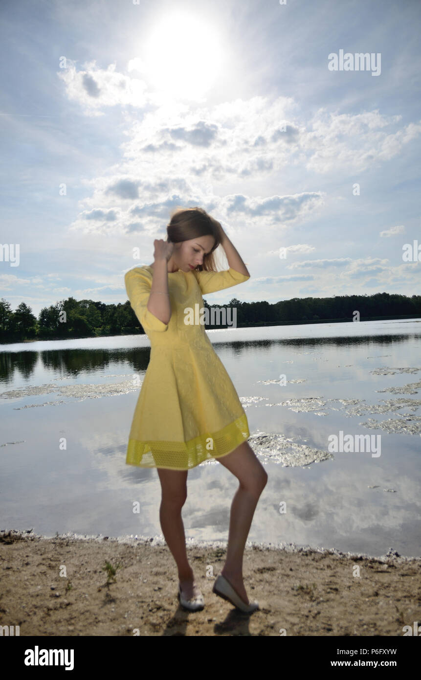 Petite woman at lake. Female model with yellow dress standing near ...