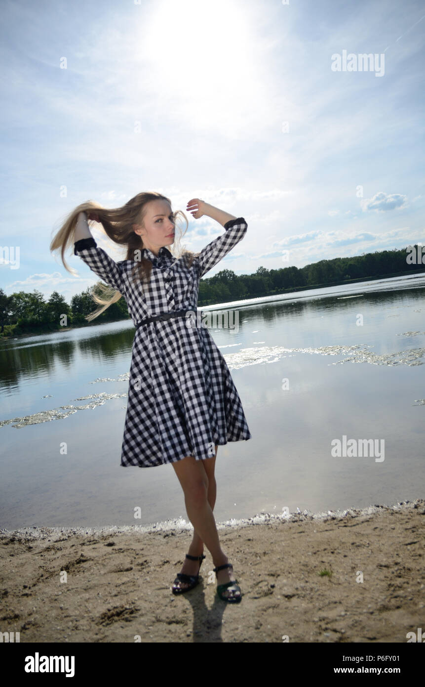 Petite woman at lake. Female model with black-white dress posing near ...