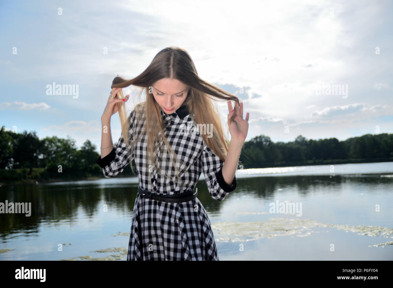 Petite woman at lake. Female model with black-white dress posing near ...