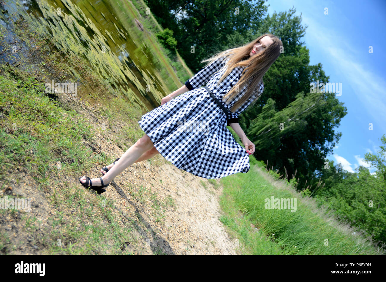 Petite woman at lake. Female model with dress walking near the water ...