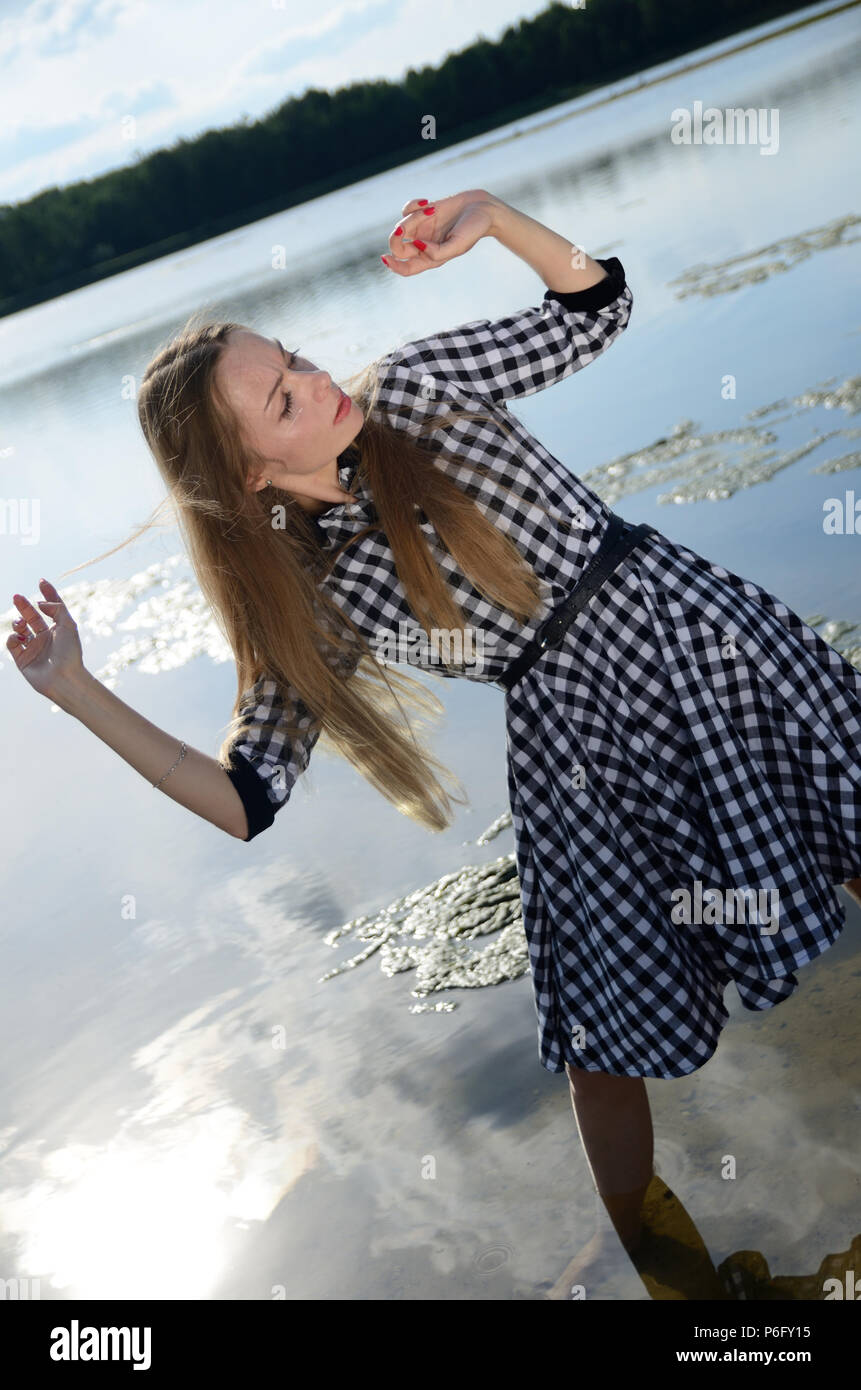 Petite woman at lake. Female model with black-white dress posing near ...