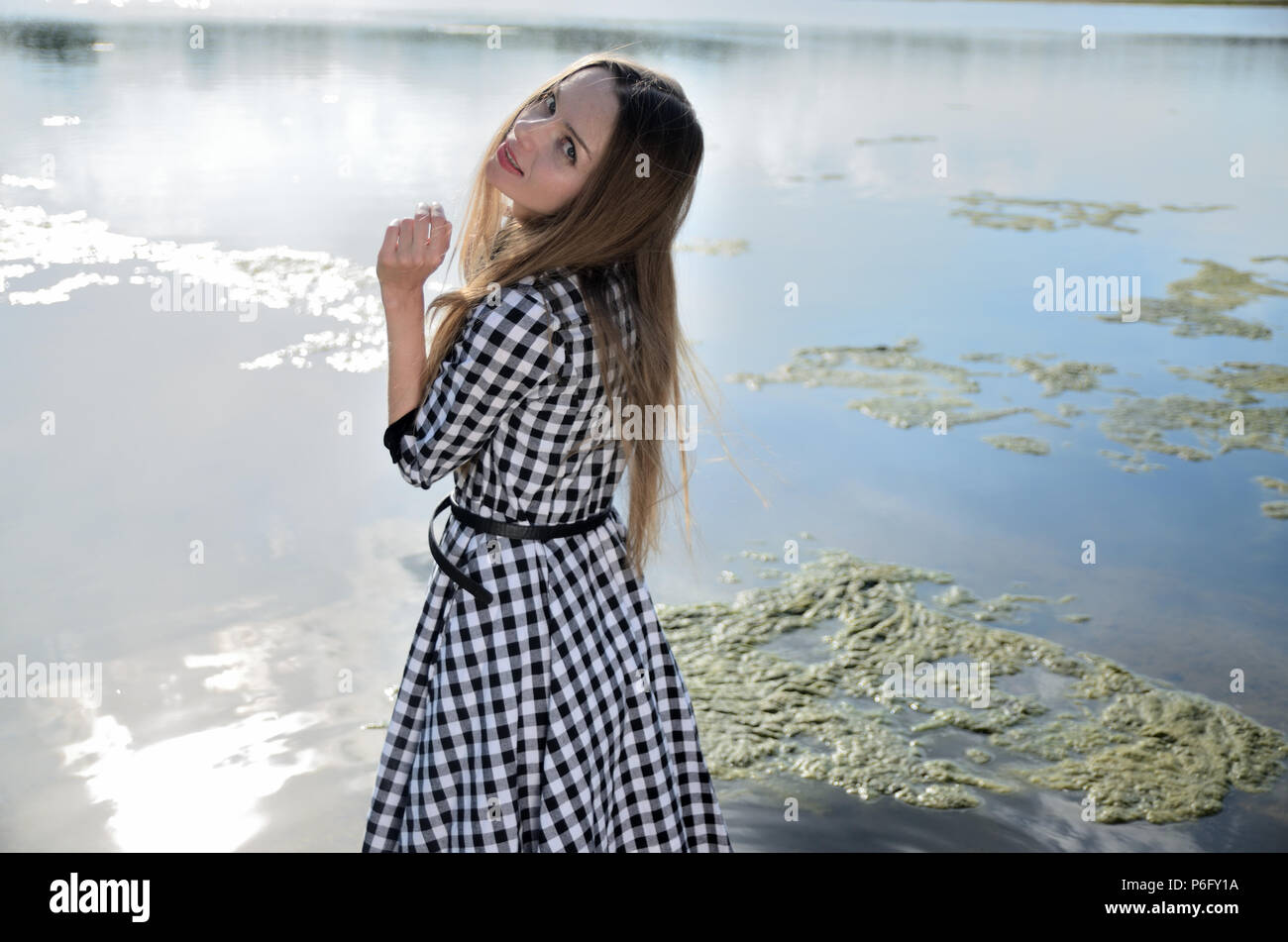 Petite woman at lake. Female model with black-white dress posing near ...