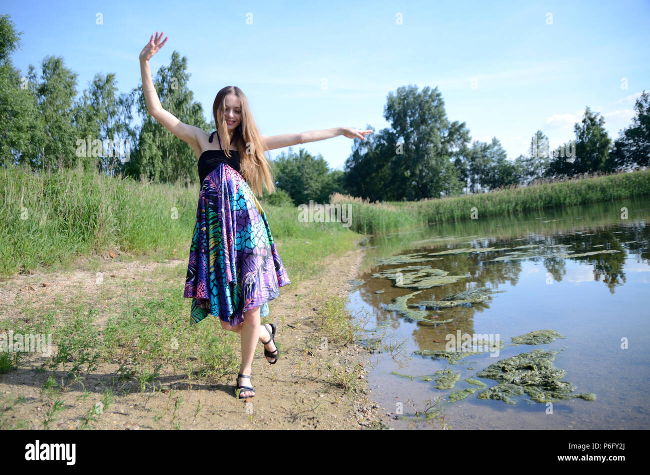 Petite woman at lake. Female model with colorful dress standing near ...