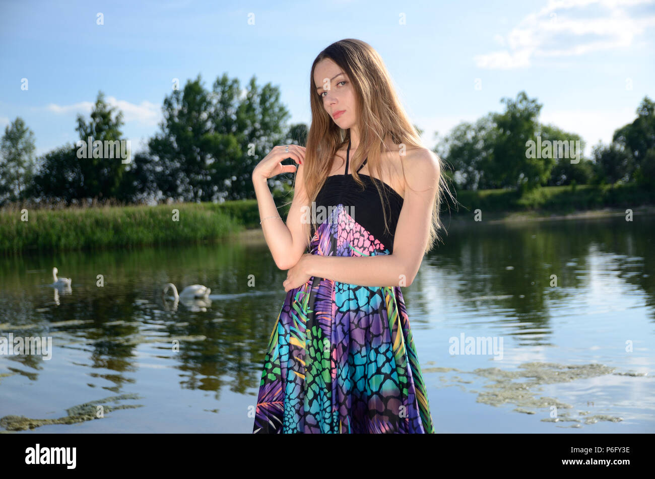 Petite woman at lake. Female model with colorful dress standing near ...