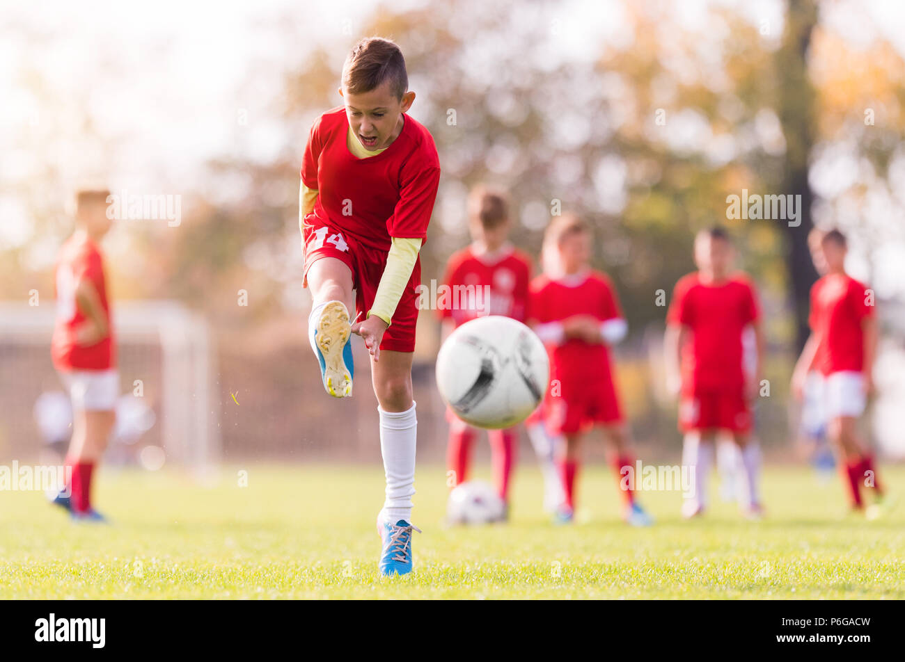 Boy kicking football on the sports field during soccer match Stock ...