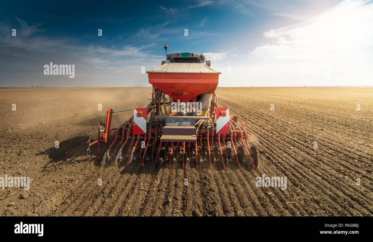 Farmer with tractor seeding - sowing crops at agricultural fields in ...