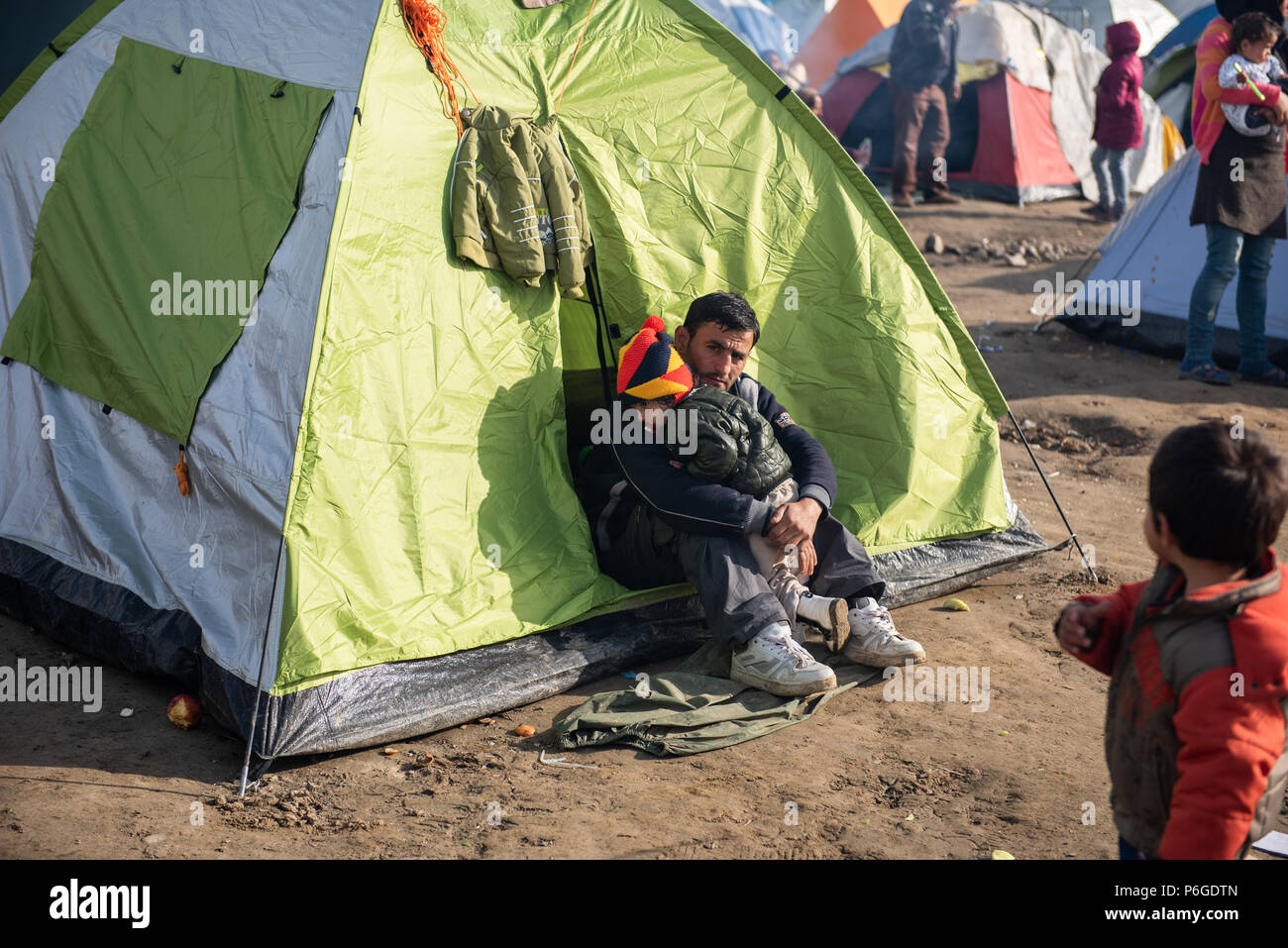 Everyday life in the camp. The man hugs his daughter sitting in front ...