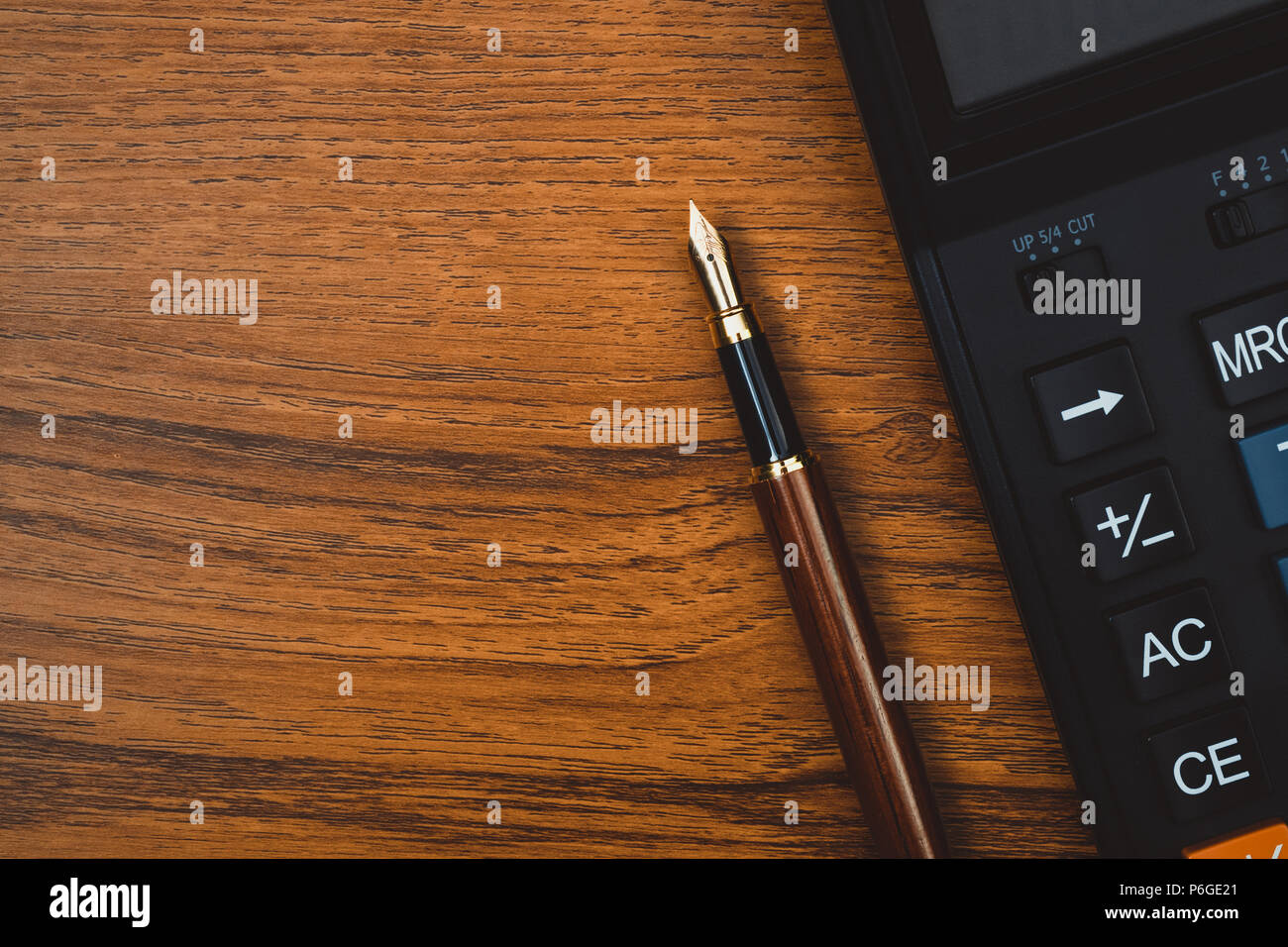 Fountain pen or ink pen with calculator on wooden working table with ...