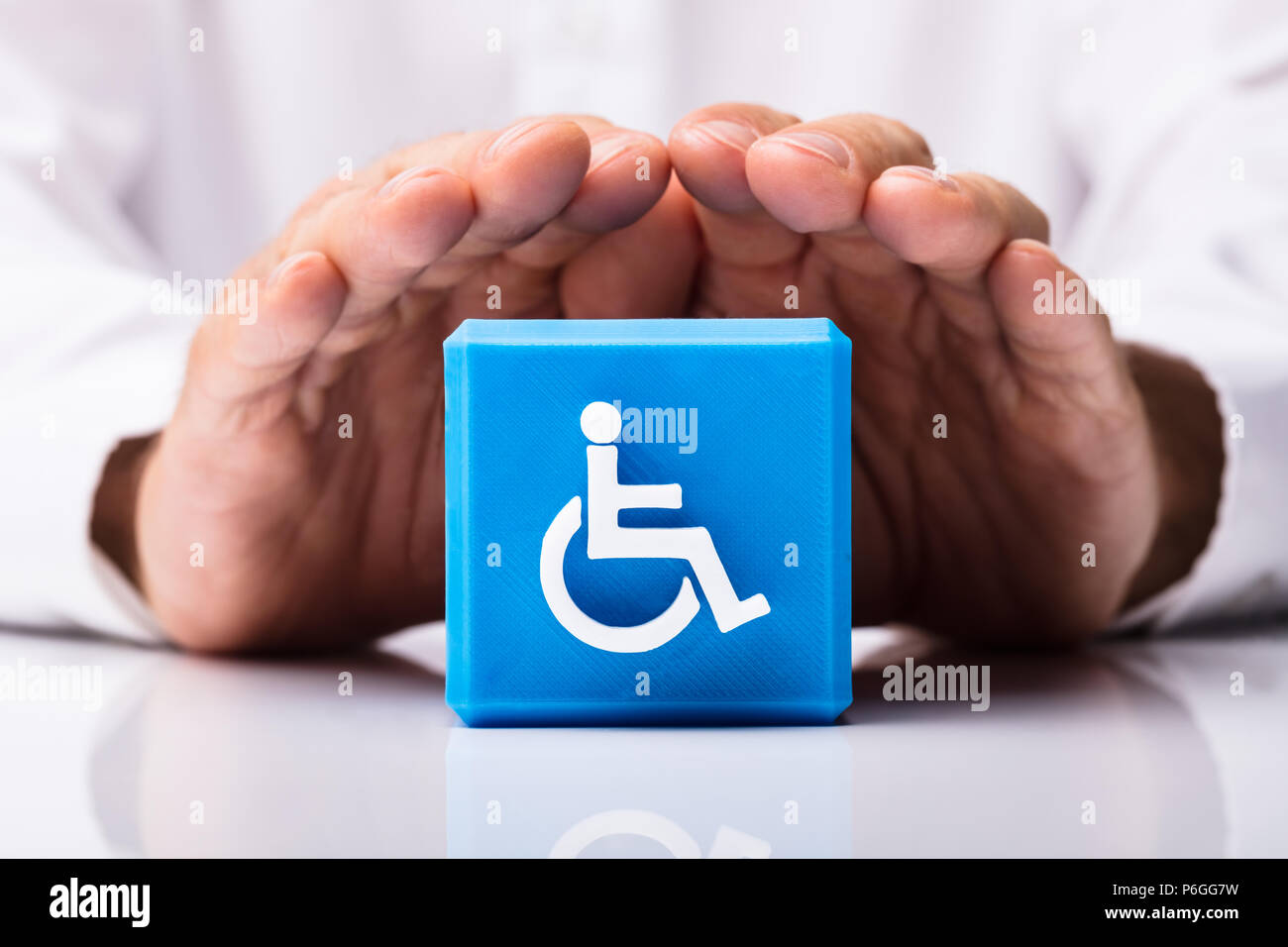 Close-up Of A Person's Hand Protecting Blue Cubic Block With Disabled ...