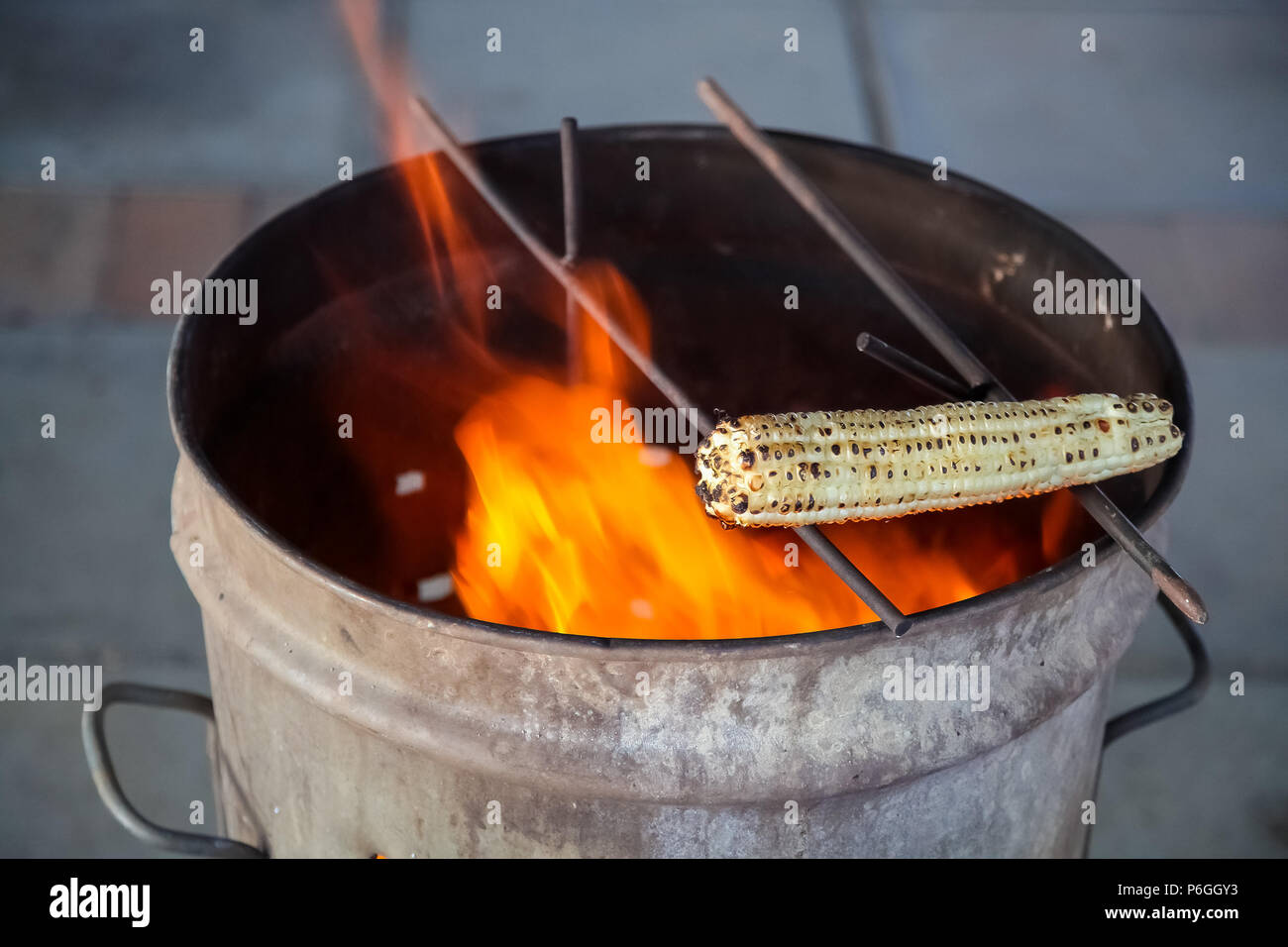 Corn on the cob maize over a bbq flame in a dustbin Stock Photo - Alamy