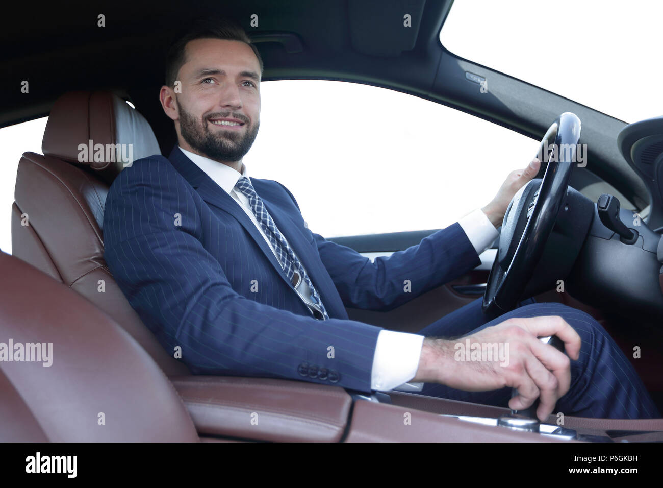 View from the side confident businessman sits at the wheel of a car ...