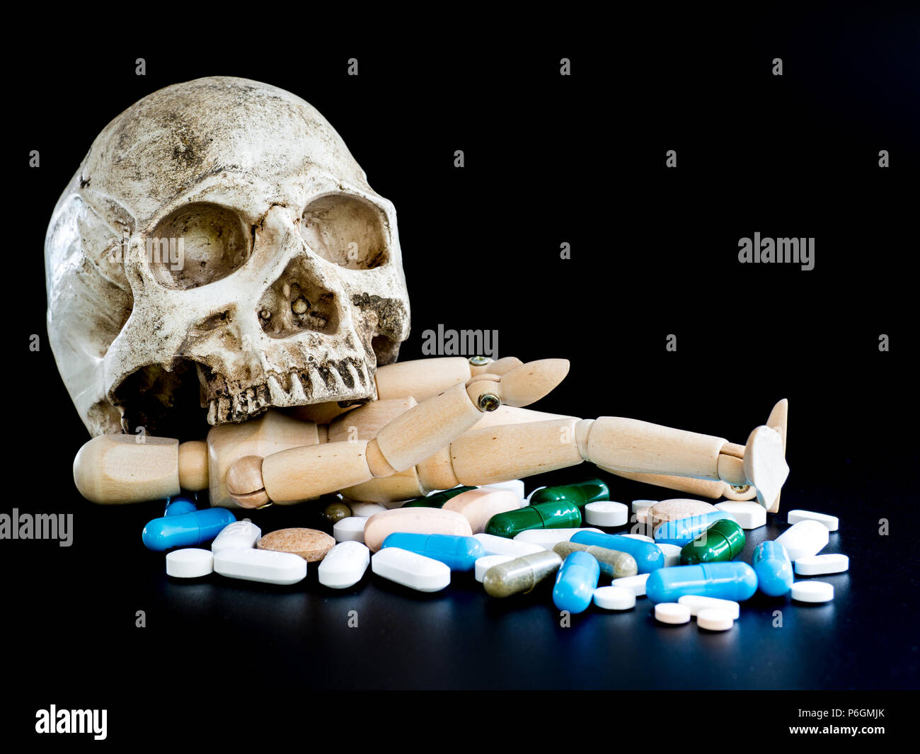 Human skull on wooden puppet multicolored of drugs and capsule is on ...