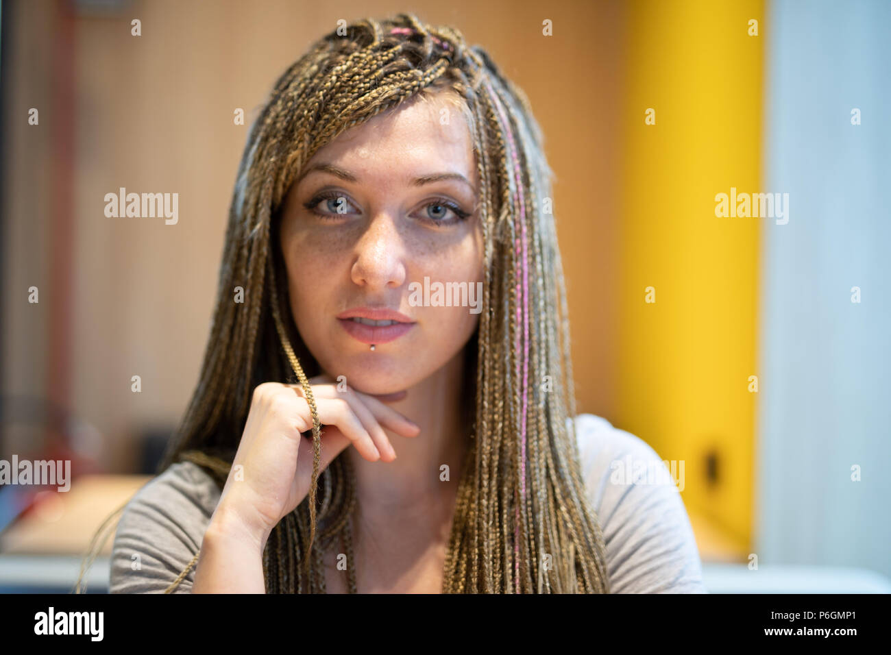 Serious attractive woman with long braided hair sitting with her hand ...