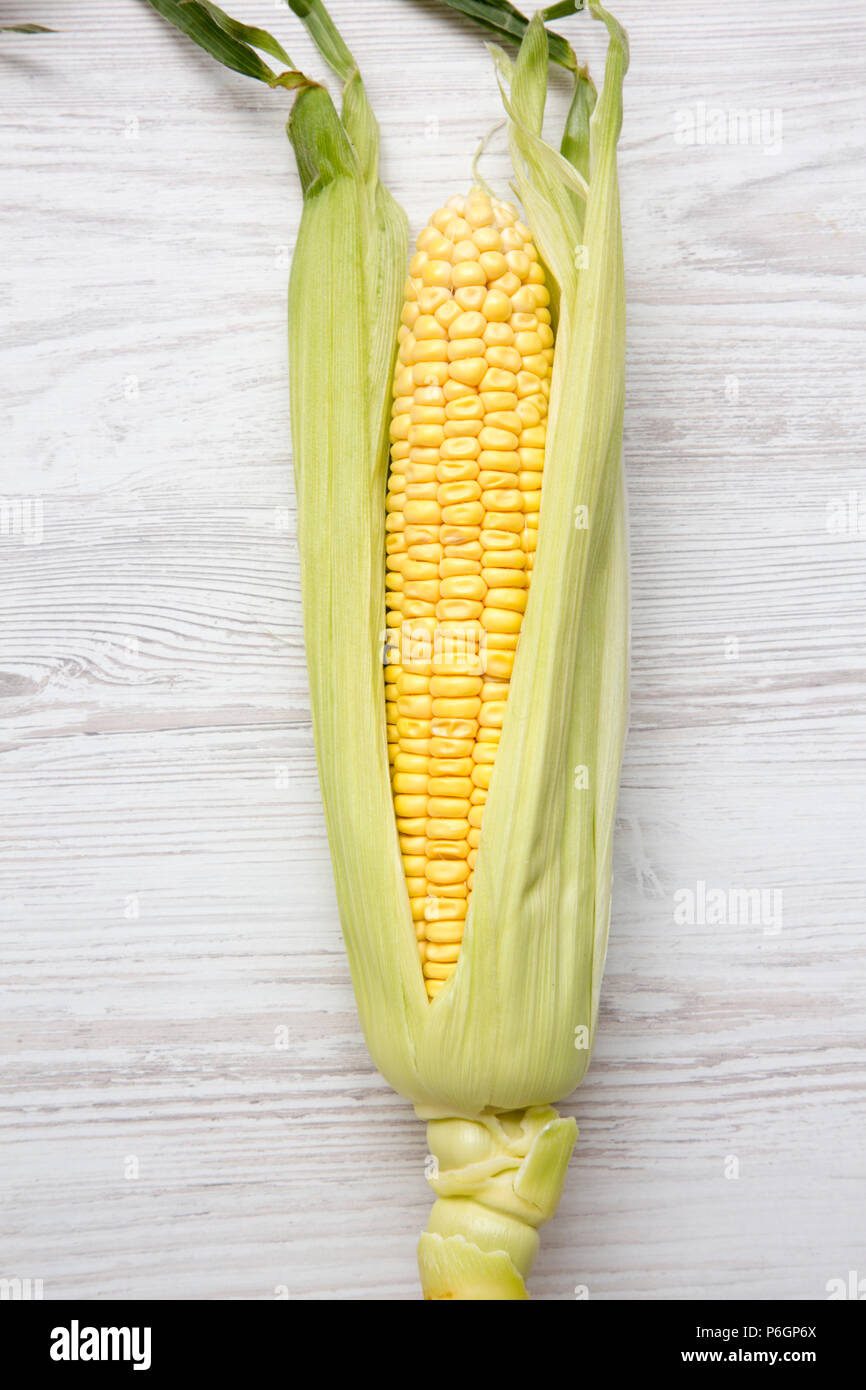 Ear of corn on a white wooden background, top view. From above, flat ...