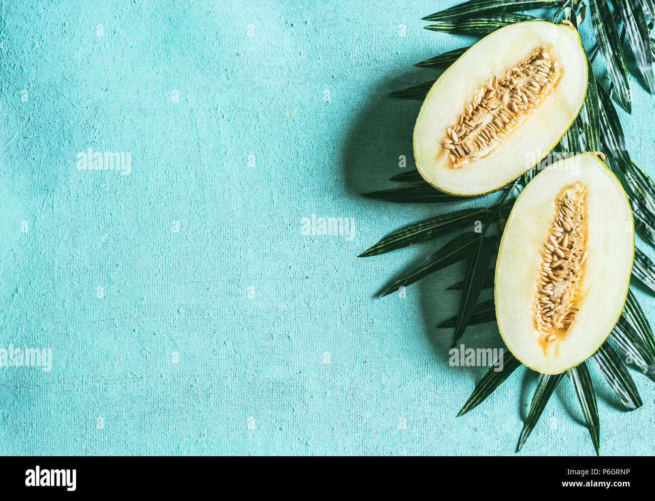 Honey melon on tropical palm leaves on turquoise blue background , top ...