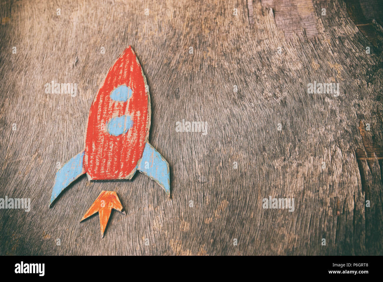 Top view image of rocket cut from paper and painted over wooden grunge ...
