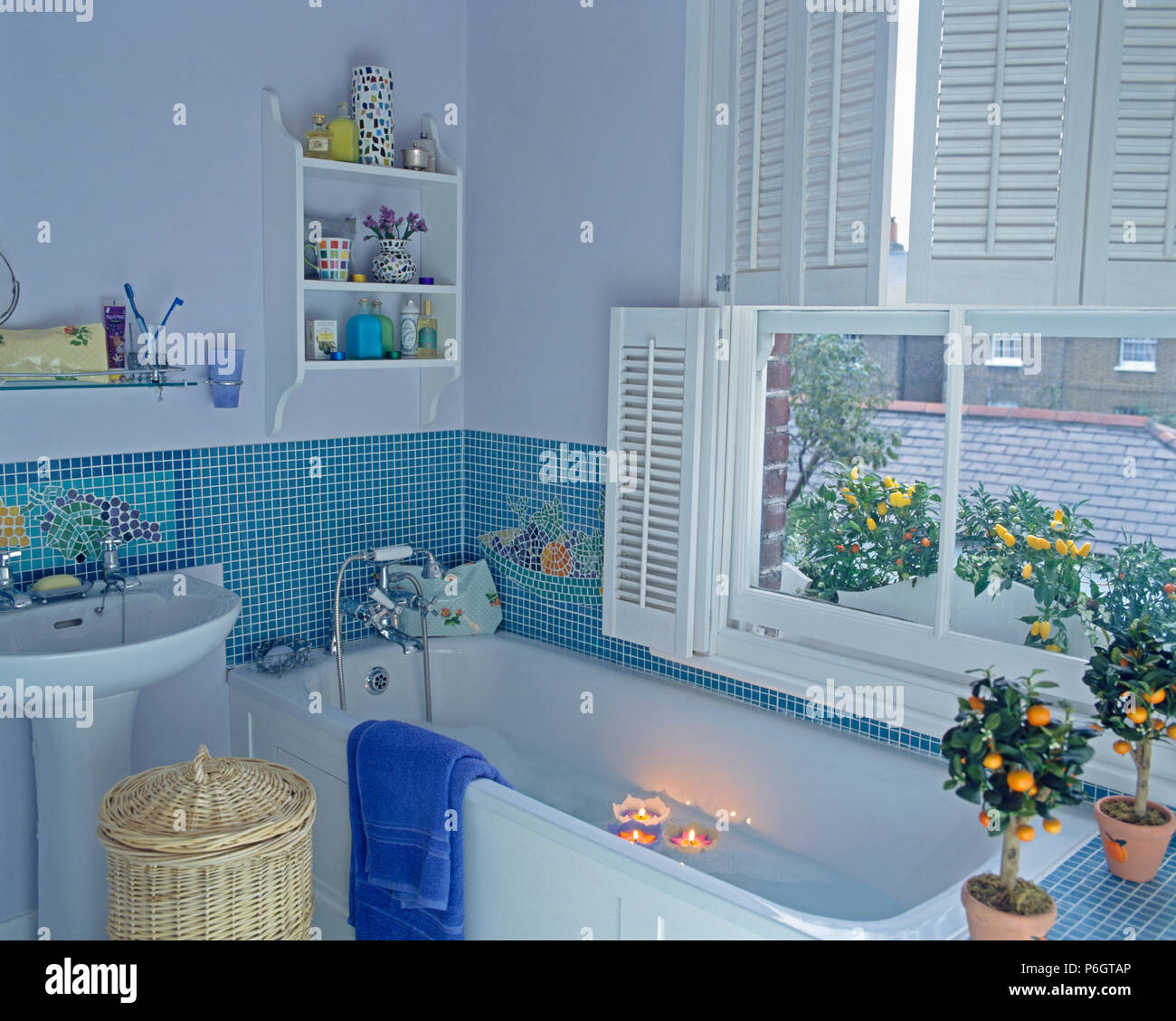 Candles floating in bath below window with white plantation shutters in ...