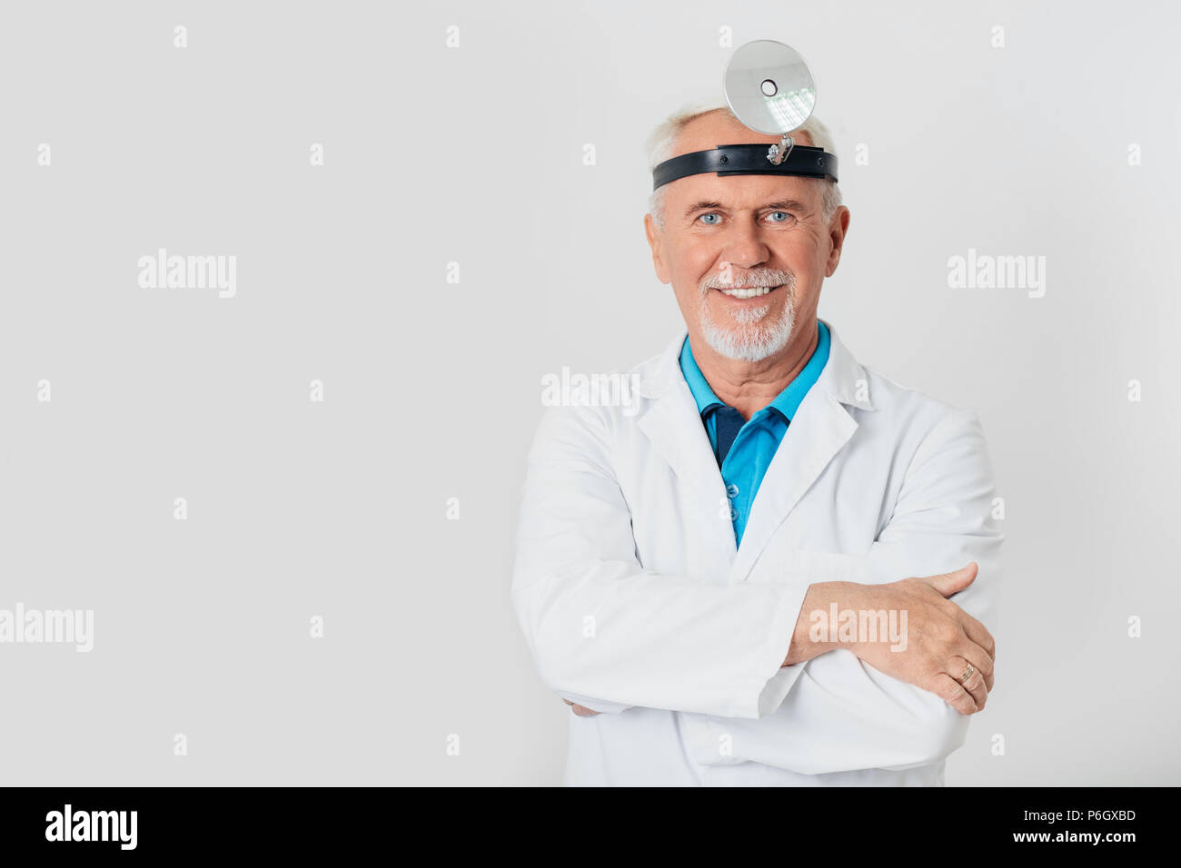 smiling ENT doctor , senior man looking at camera while standing white ...