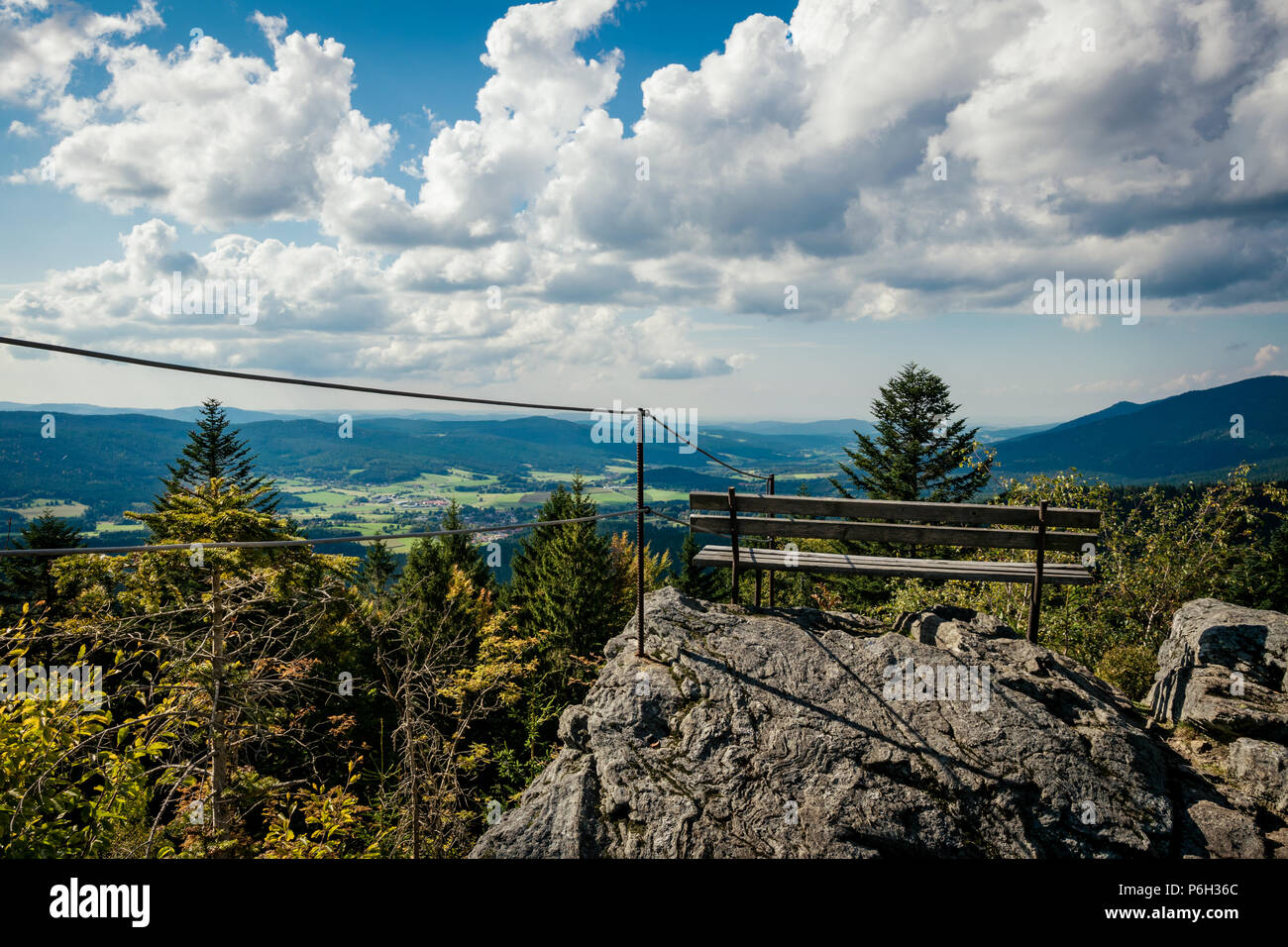 Bench on top of a mountain on the rock with clouds on the sky and a ...