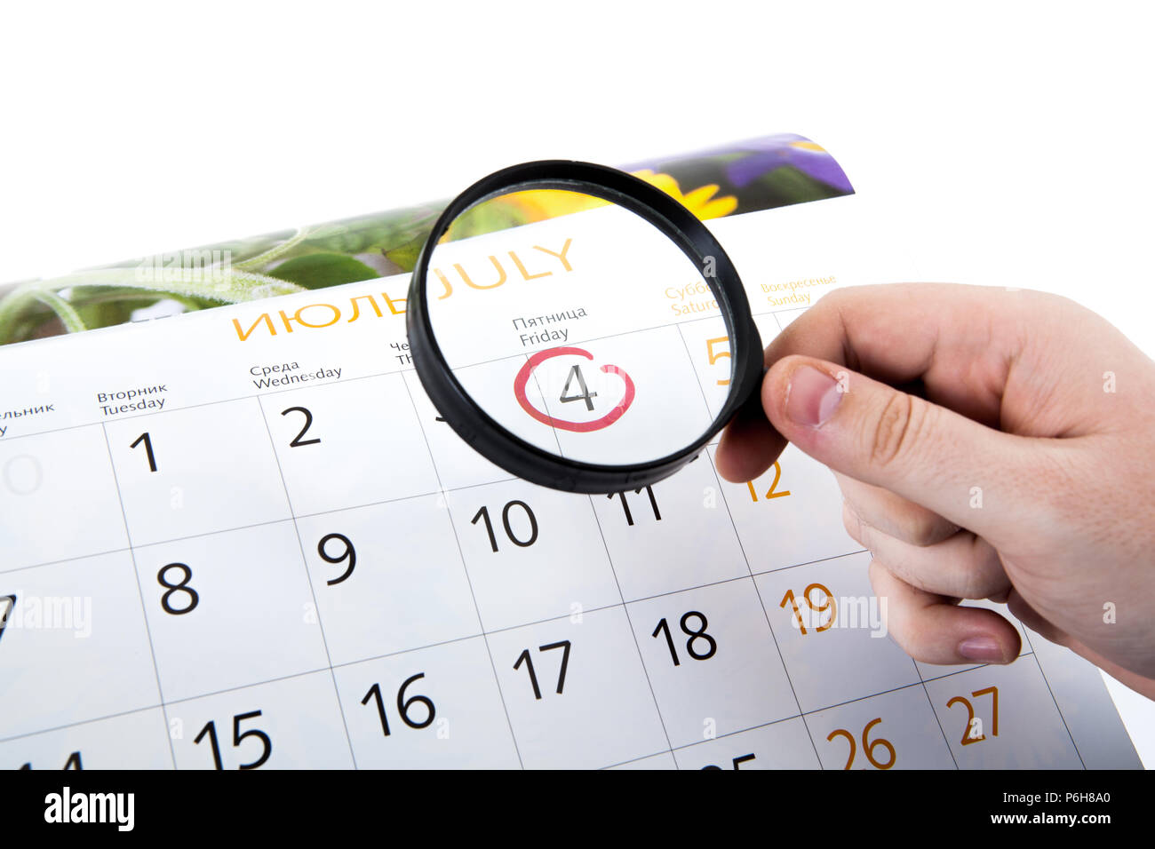 Magnifying glass in hand and the wall calendar isolated on white ...