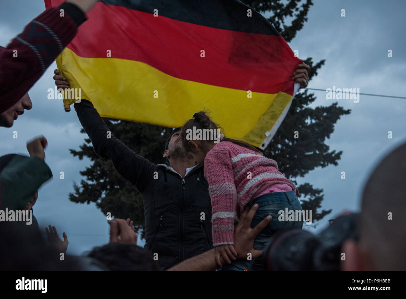 Refugees wave a German flag as they call for borders to be open and ...