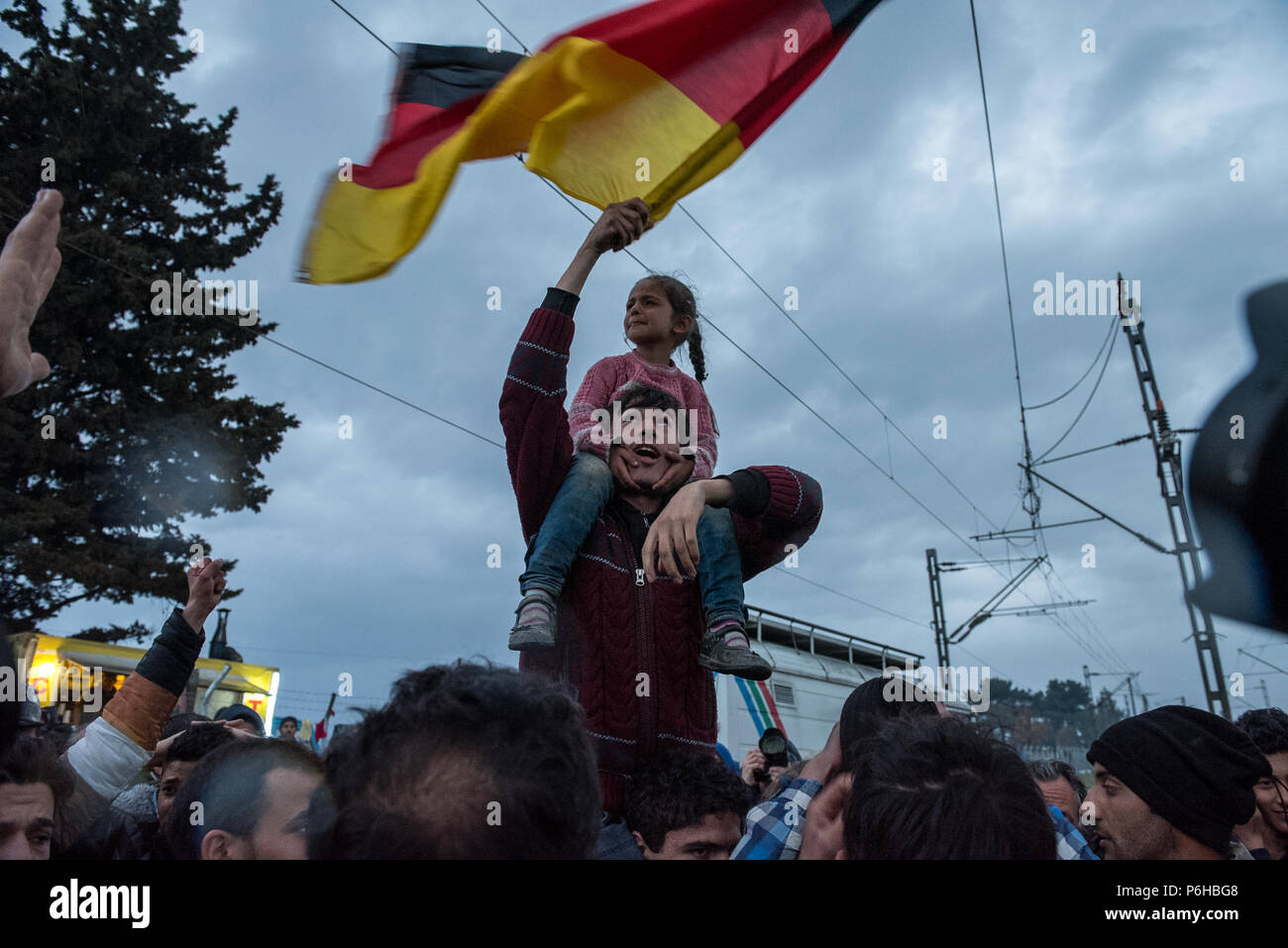 Refugees wave a German flag as they call for borders to be open and ...