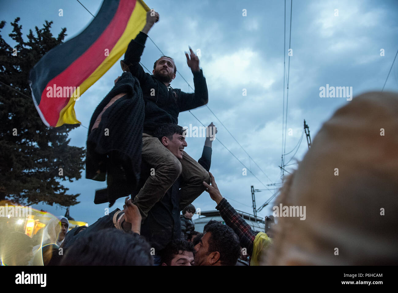Refugees wave a German flag as they call for borders to be open and ...