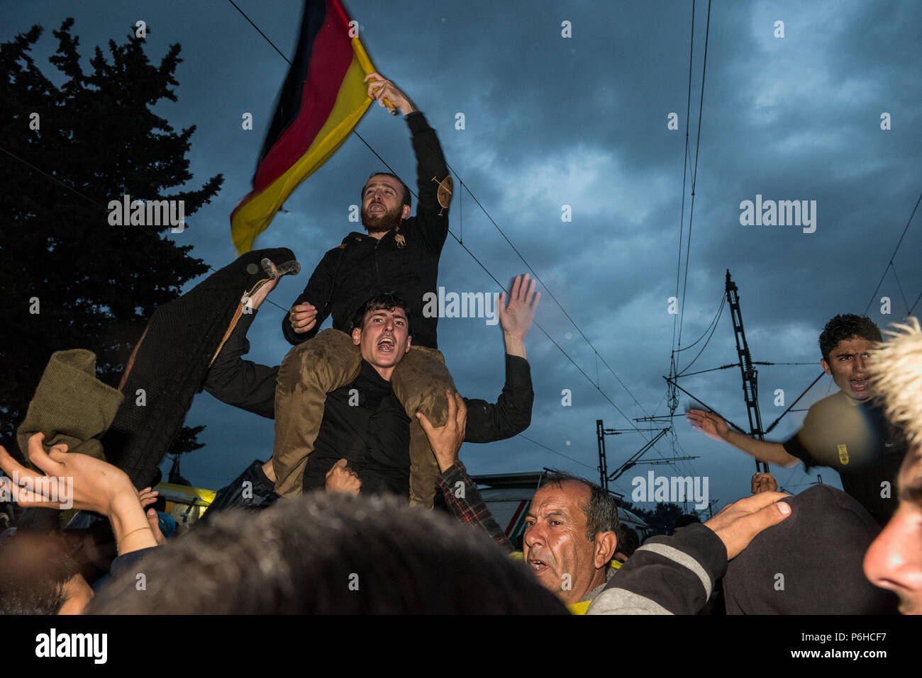 Refugees wave a German flag as they call for borders to be open and ...