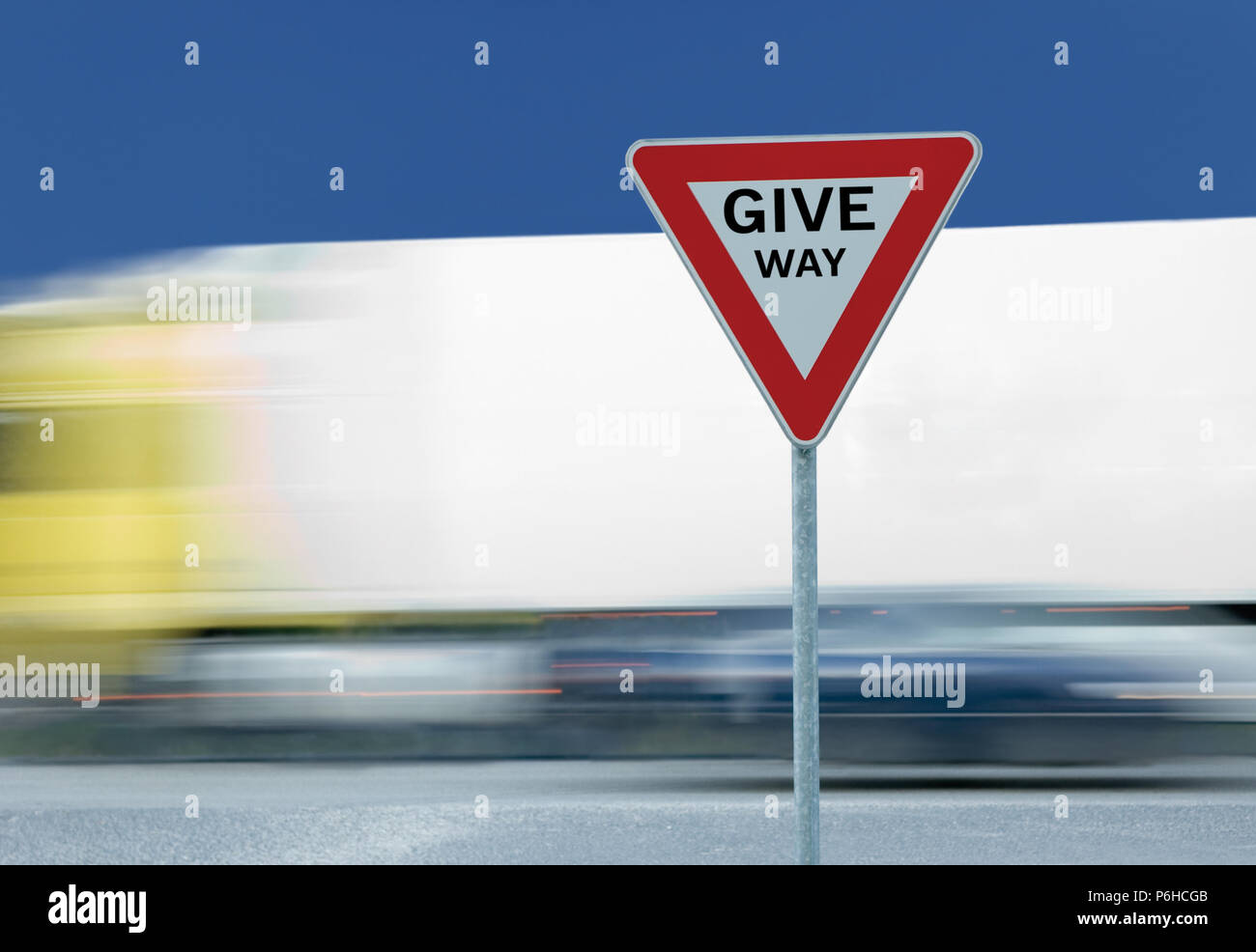 Give way yield text road sign and truck traffic in the motion blurred ...