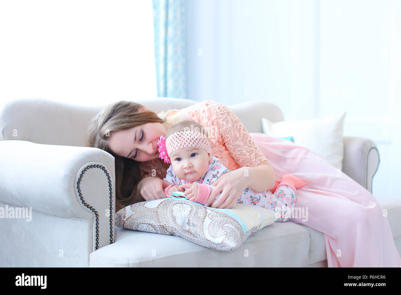 Young caucasian mother sitting with child on sofa and wearing pink ...