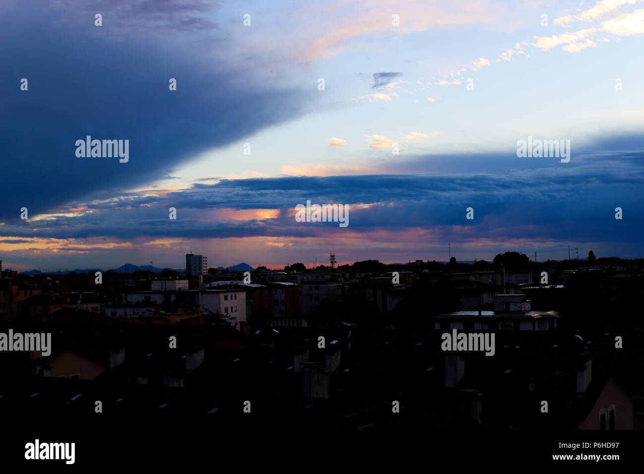 Charming evening city in sunset sky background Stock Photo - Alamy