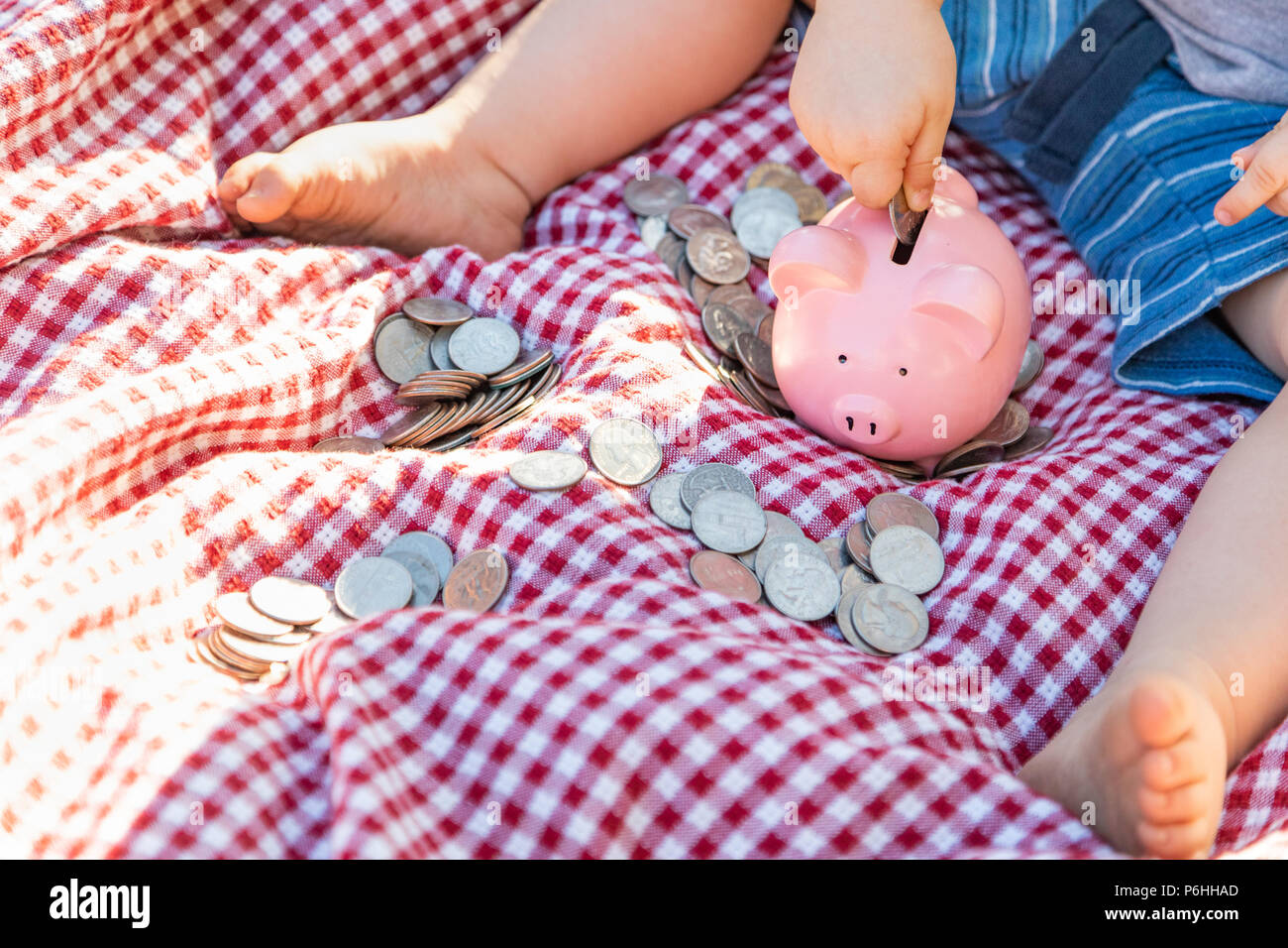 Baby Boy Sitting on Picnic Blanket PUtting Coins in Piggy Bank Stock ...